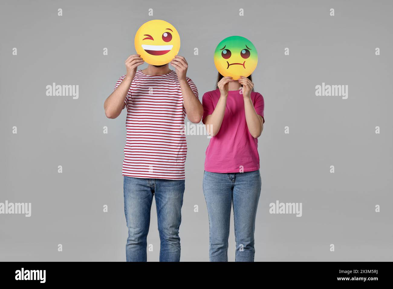 People covering faces with emoticons on grey background Stock Photo - Alamy
