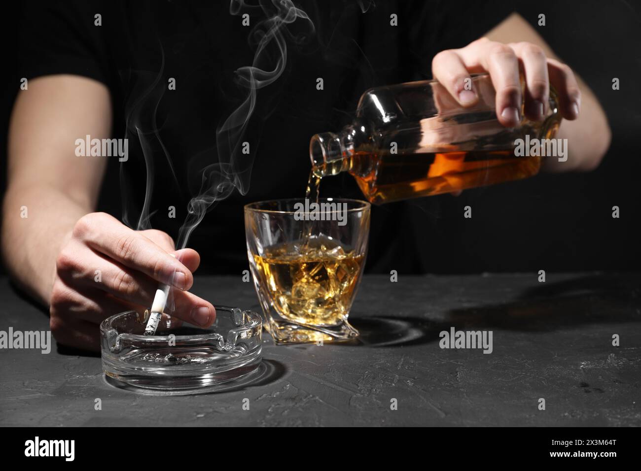 Alcohol addiction. Man with smoldering cigarette pouring whiskey into ...
