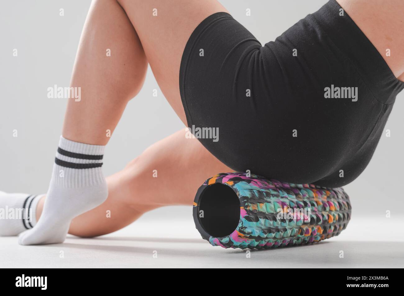 Faceless woman doing roller exercise for myofascial release on white ...
