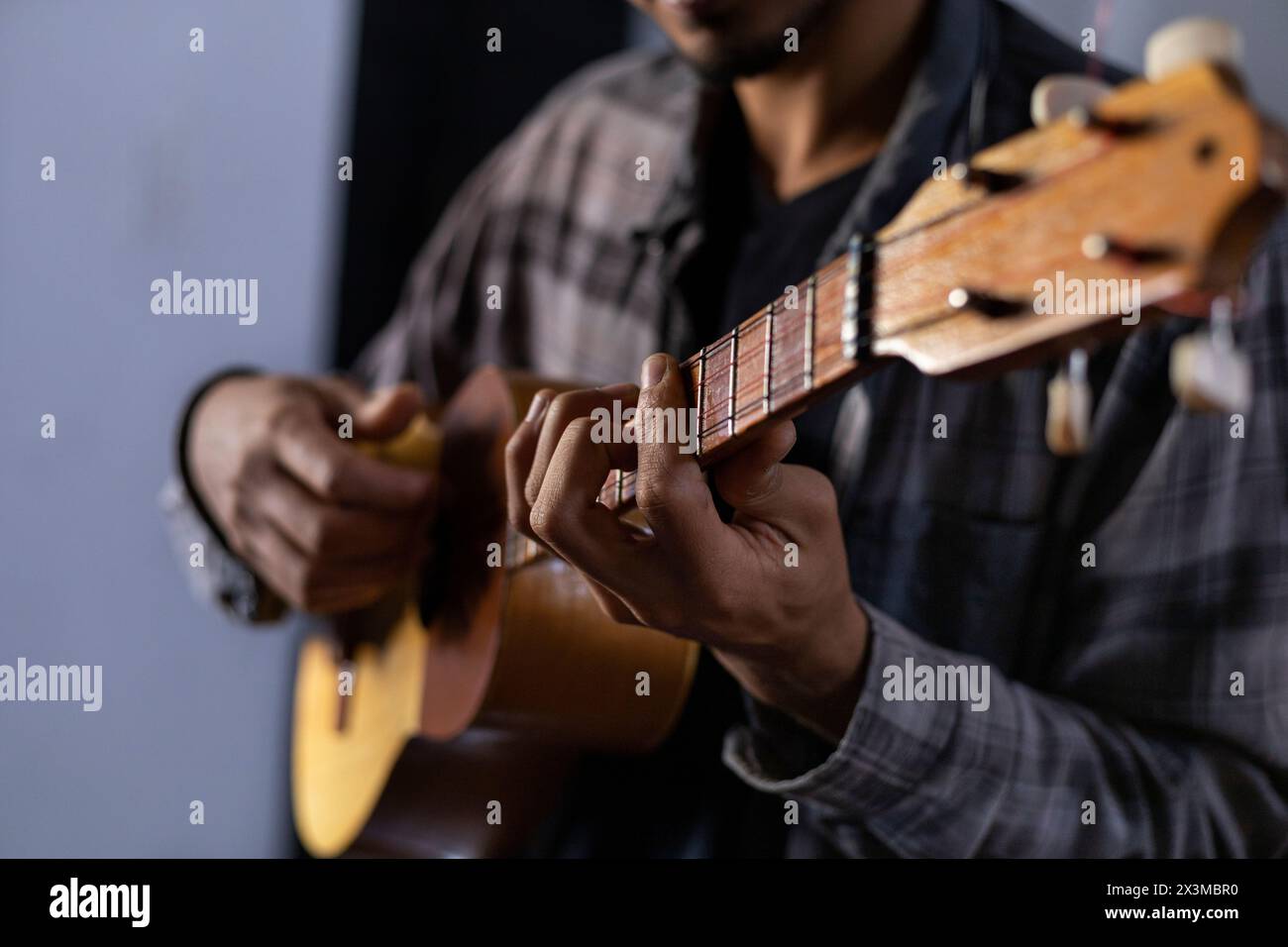 Latin American young man (24) playing a "Cuatro", a typical Venezuelan ...