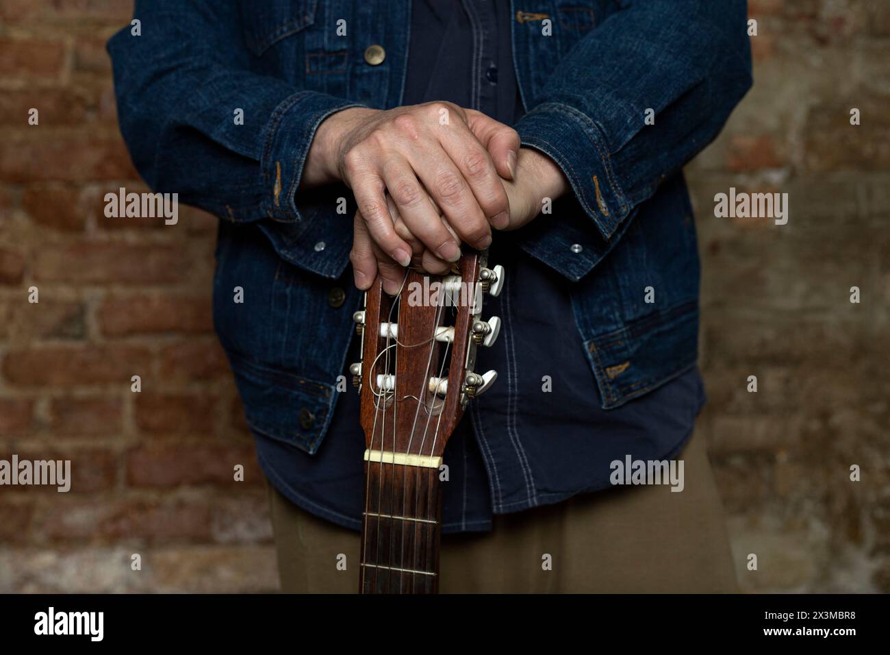 Medium shot of adult male hands on the headstock of a classical guitar ...