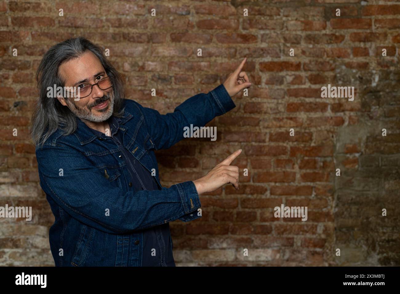 Latin American man (44) with long gray hair, blue jeans jacket points ...