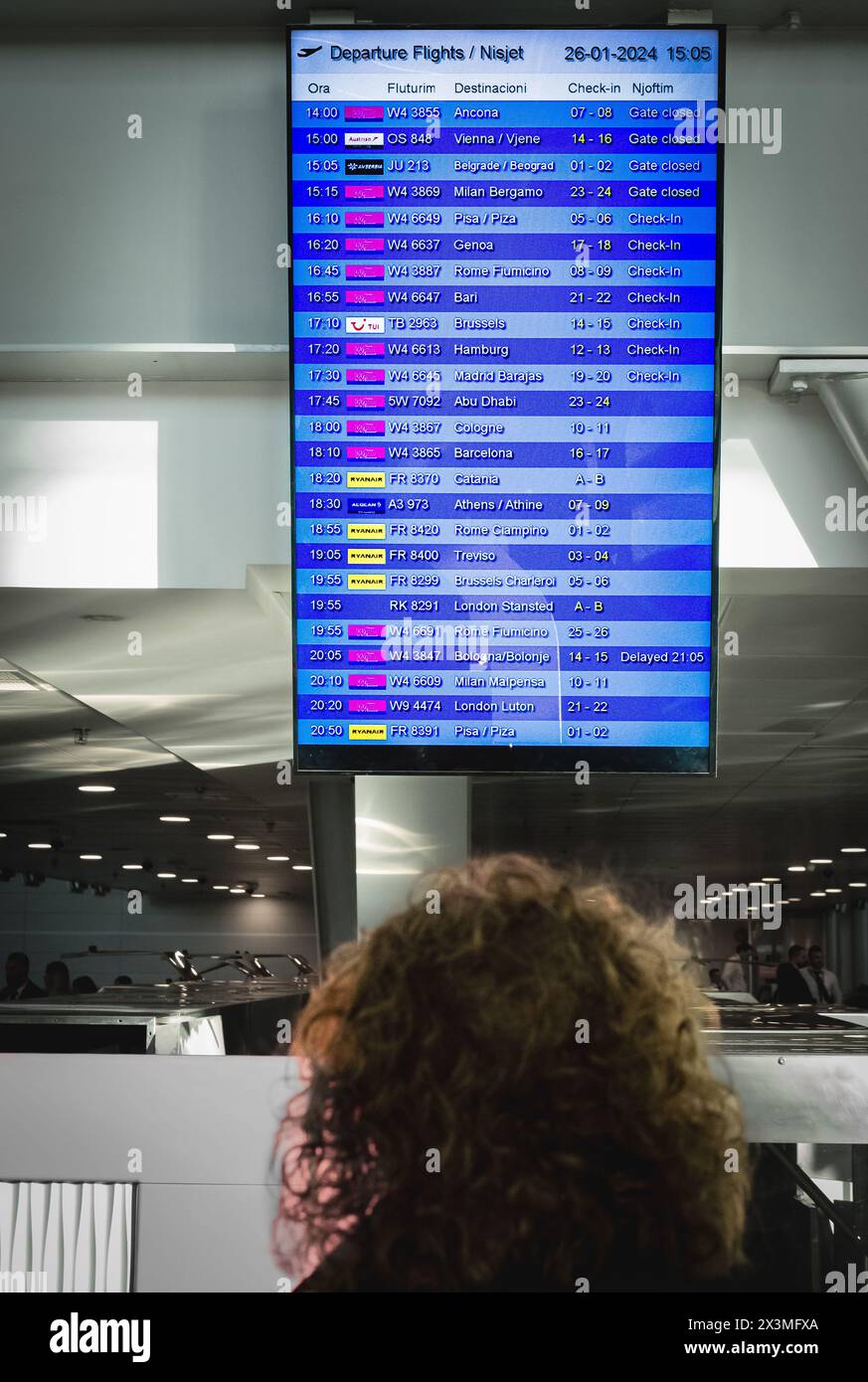 Woman looking at the flight information board, checking her flight in ...