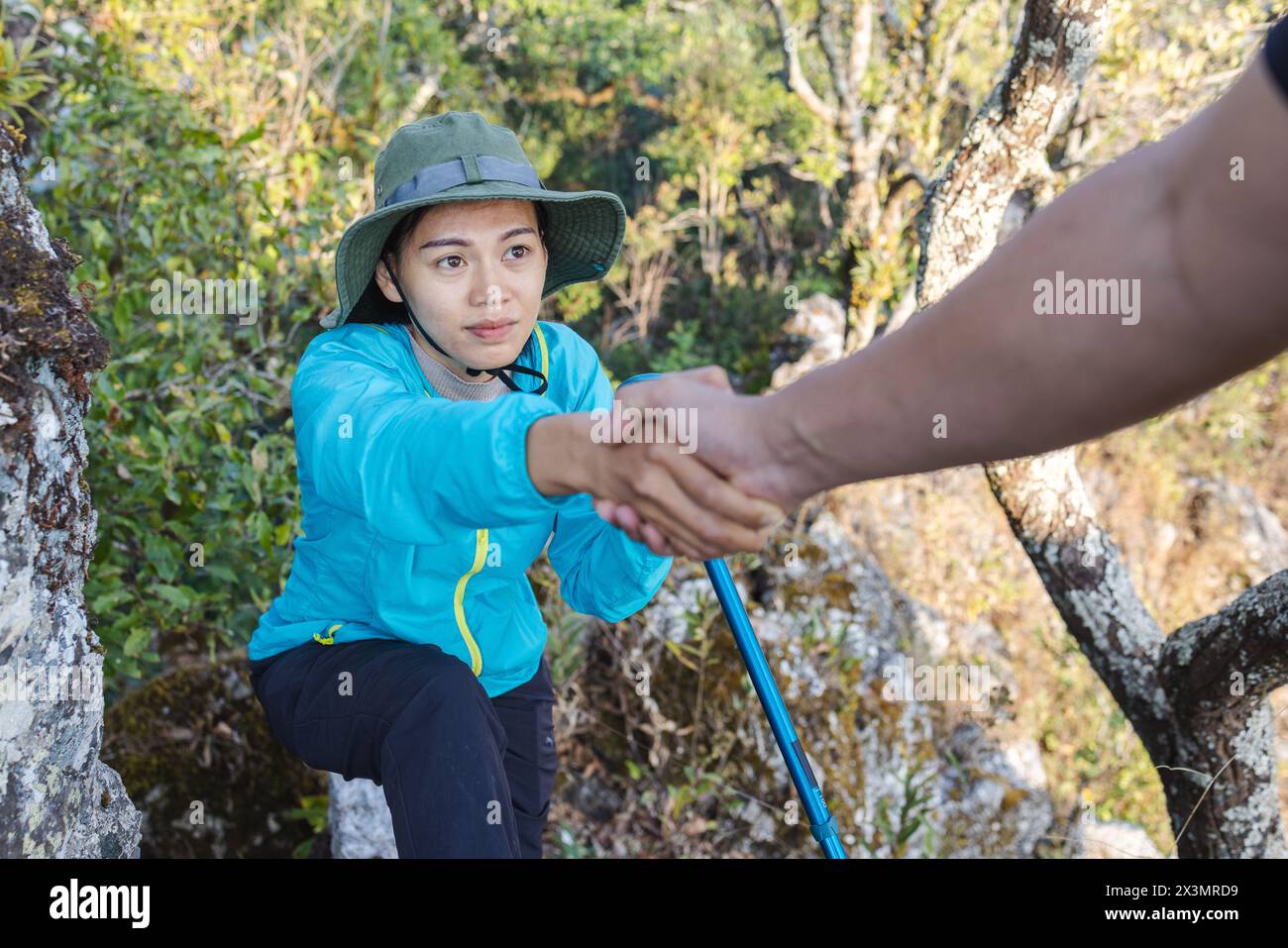 Person women hikers climbing up mountain cliff and one of them giving ...