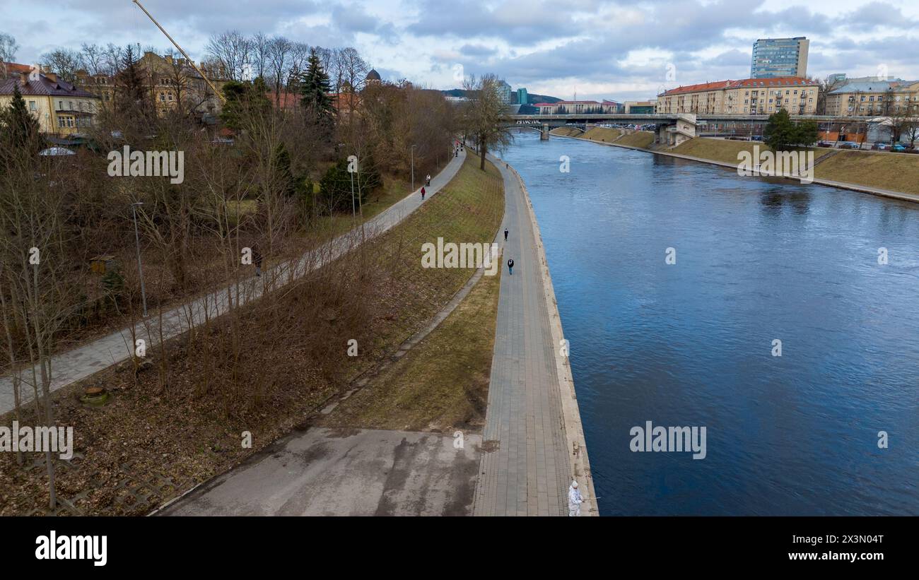 Drone photography of river shoreline going through city and people ...