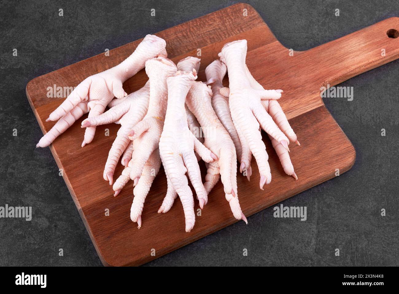 Raw chicken feet on board on black background Stock Photo - Alamy