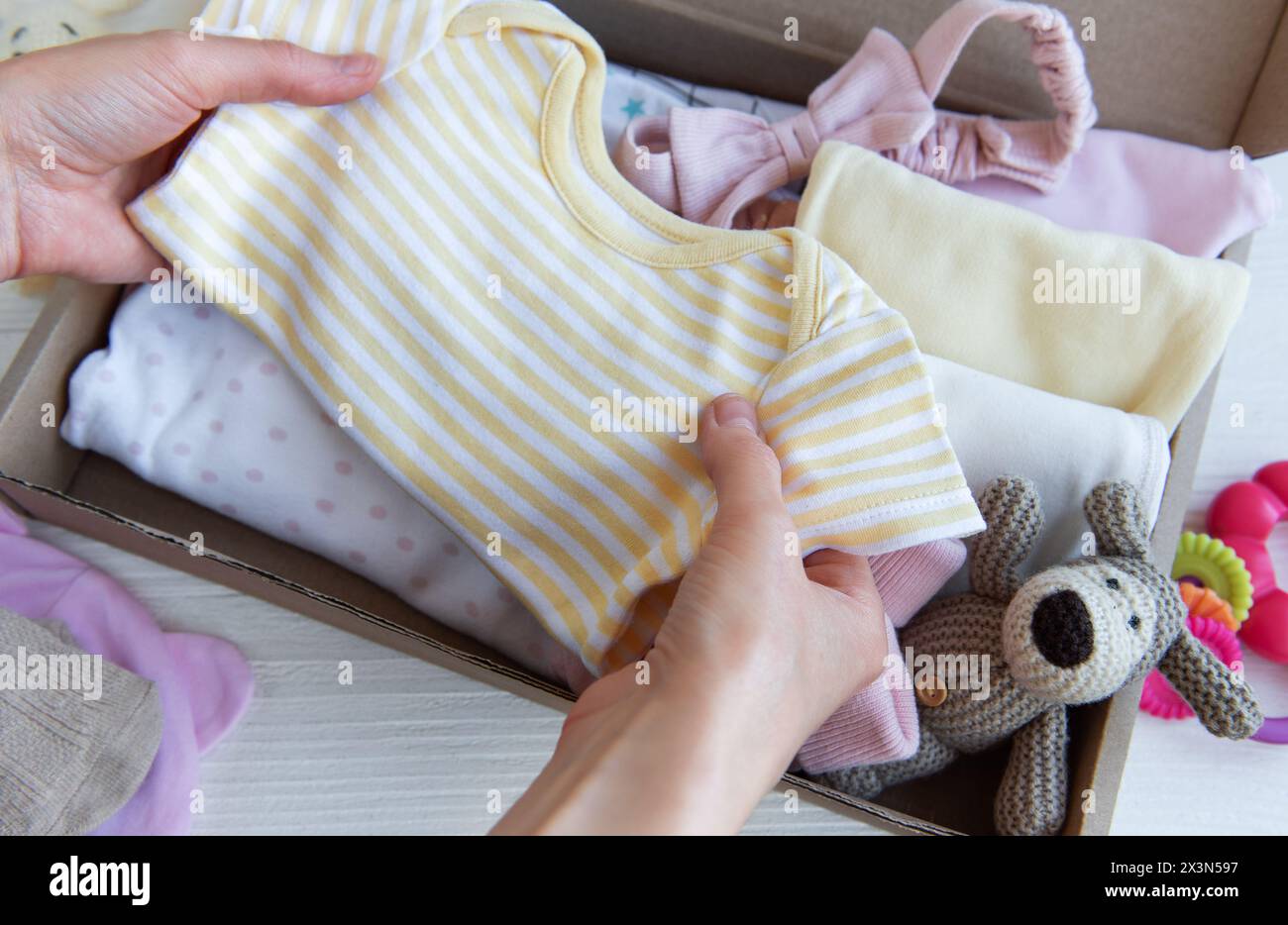 Women's hands collect children's clothes into boxes. The concept of ...