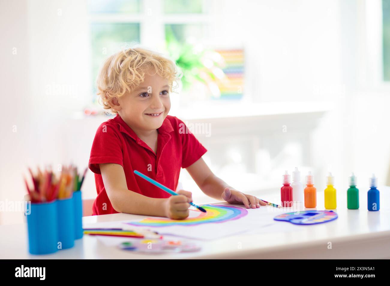 Kids paint. Child painting in white sunny study room. Little boy ...