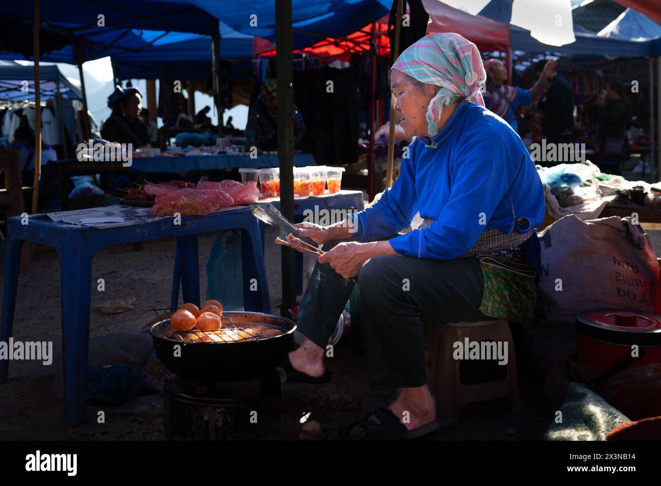 Woman cooking at a food stall at the Can Cau Market in Lao Cai Province ...