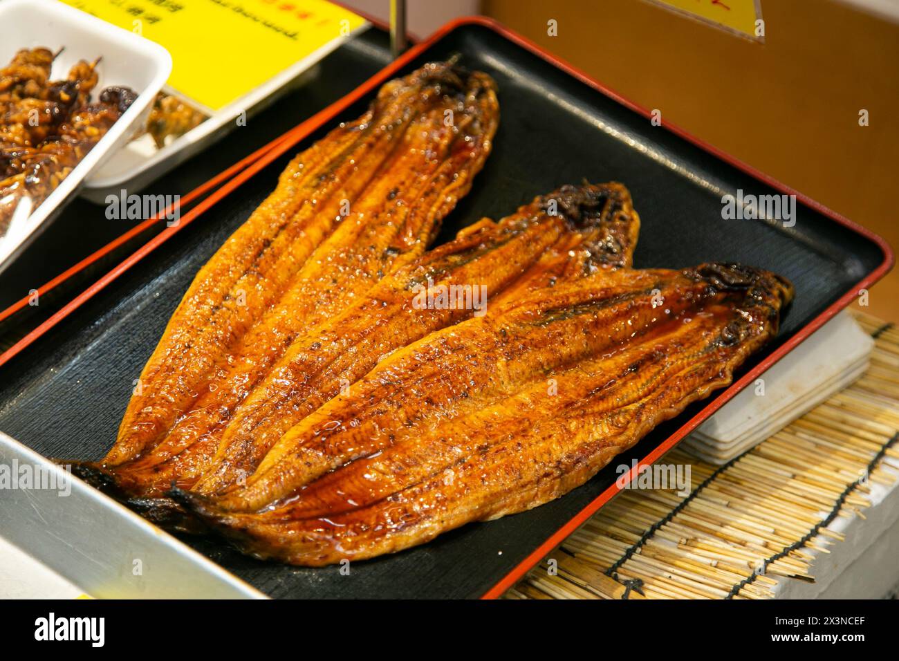 Roasted skewered eel at a food market in the city of Osaka in Japan ...