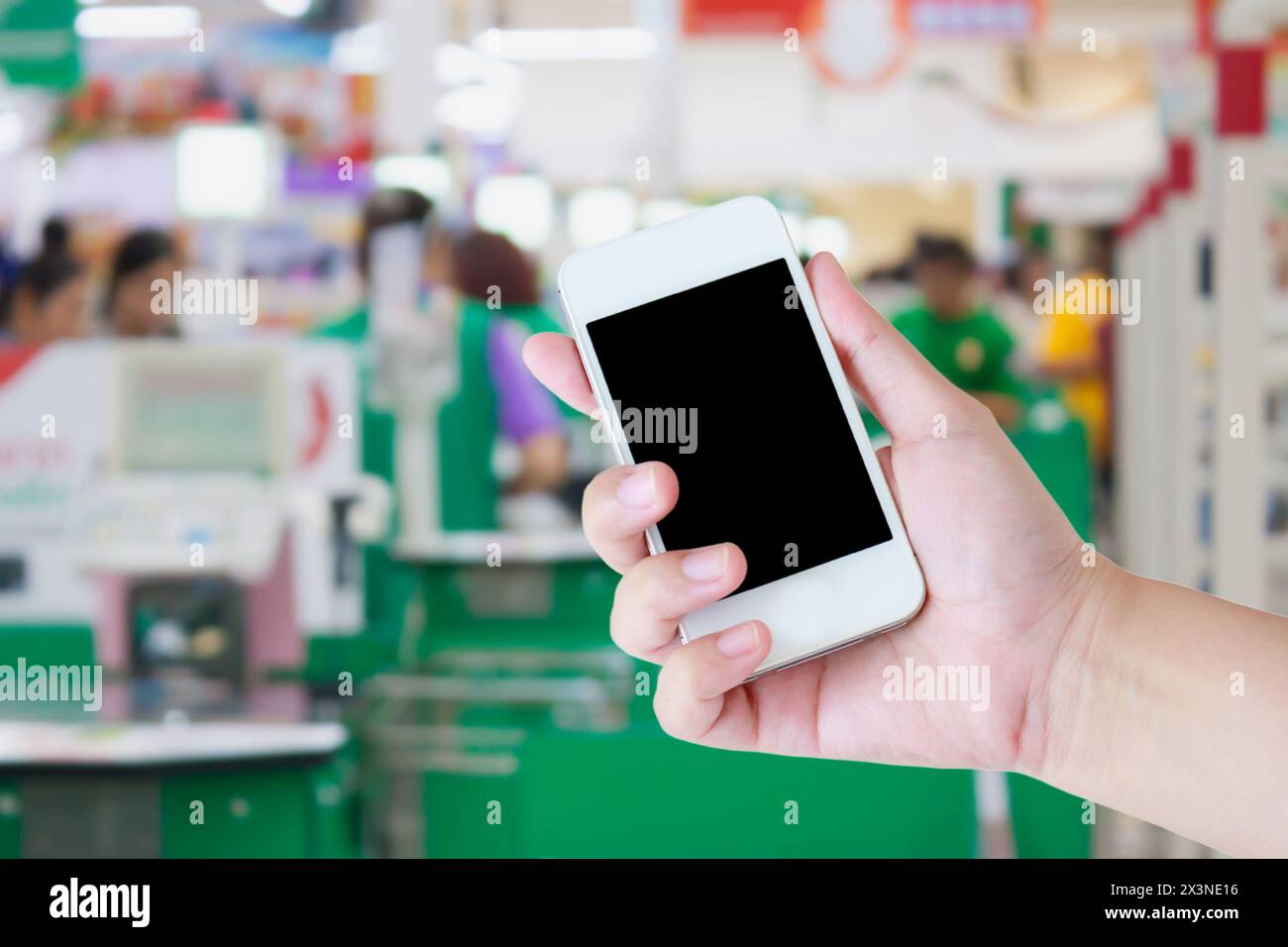Hand holding mobile phone at supermarket checkout background, digital ...