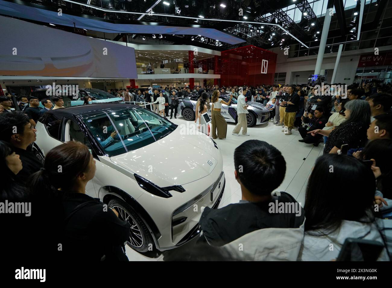 Visitors watch artists perform near vehicles at the Zeekr booth during ...