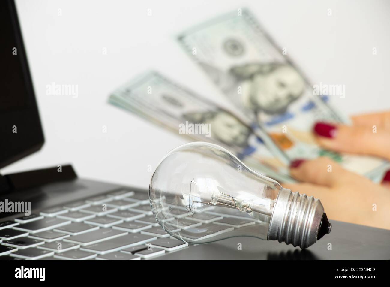 A girl counts dollars against the background of an incandescent light ...