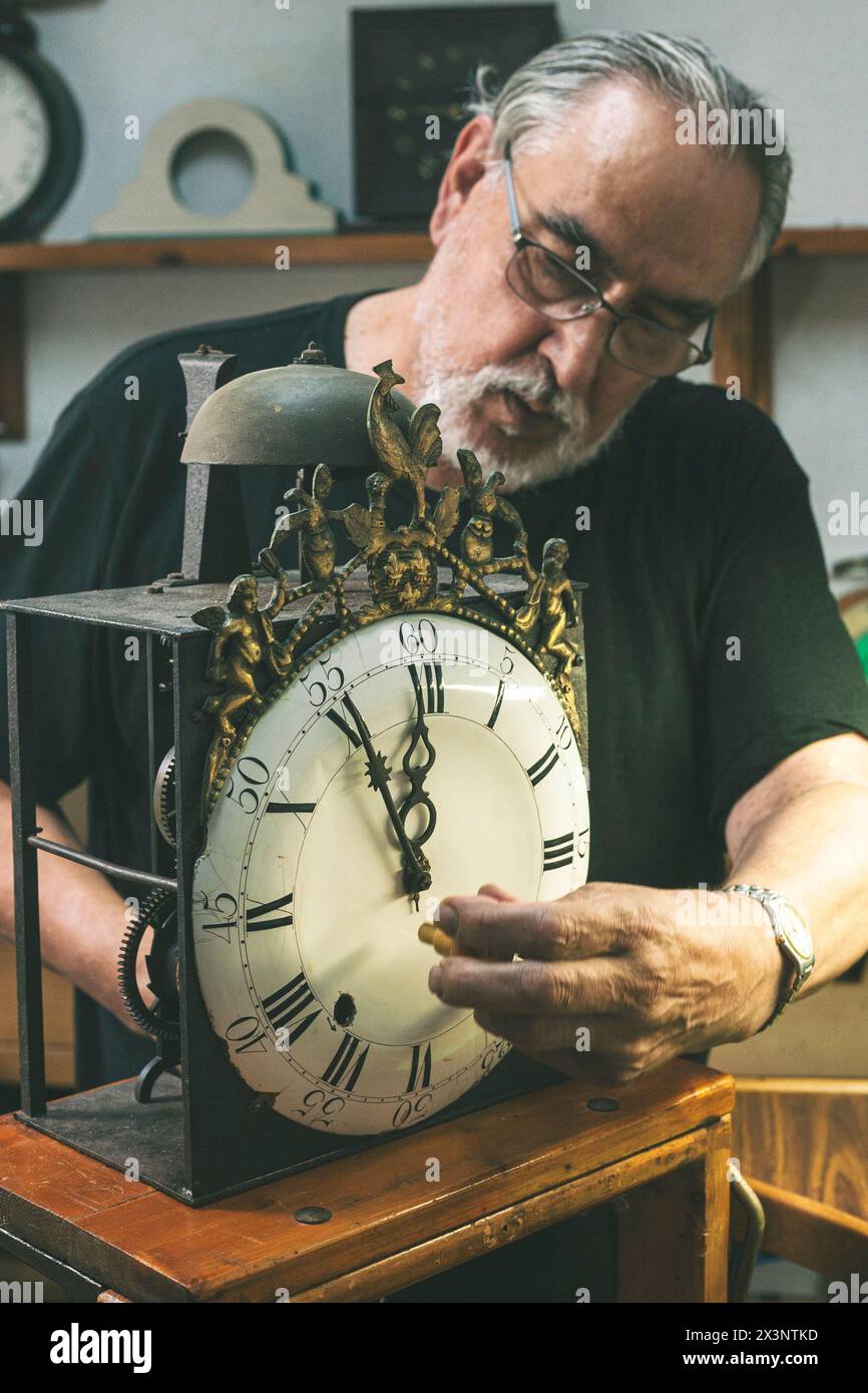 Front shot of a watchmaker repairing a large antique clock. You can see ...