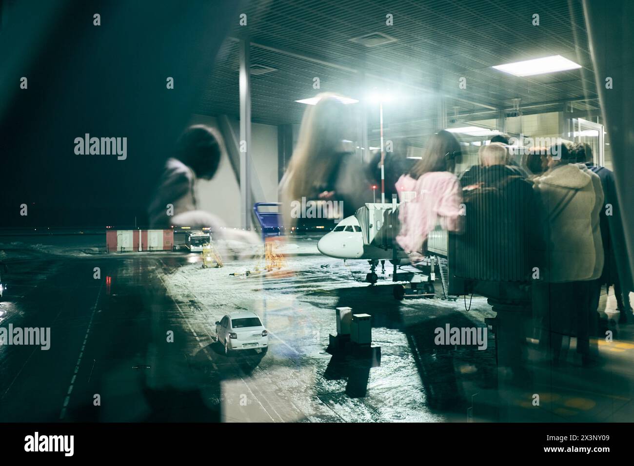 Reflection in the window at passengers and their luggage walking along ...