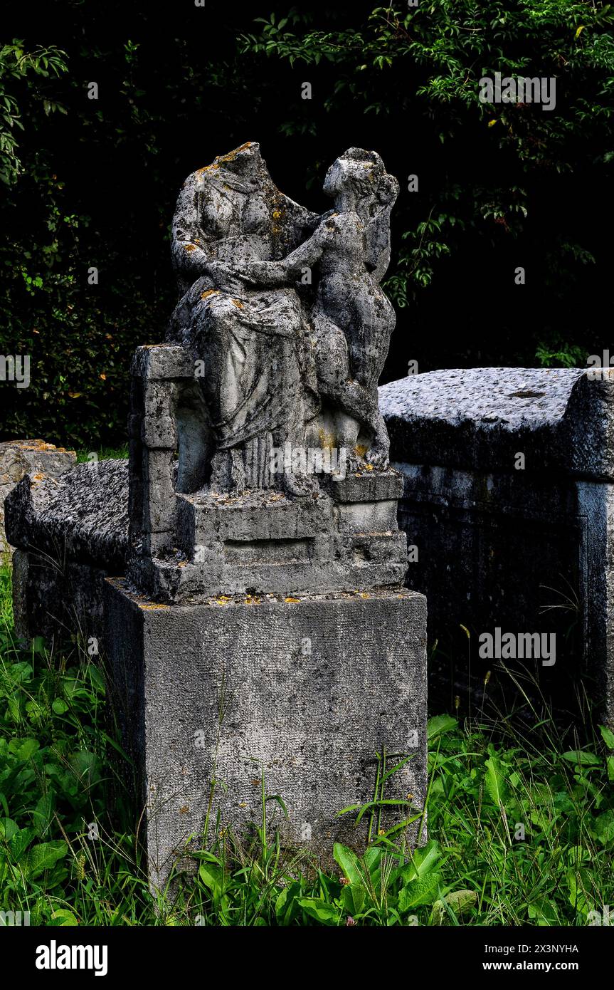 A seated woman, now headless, embraces a winged child. Amid family ...