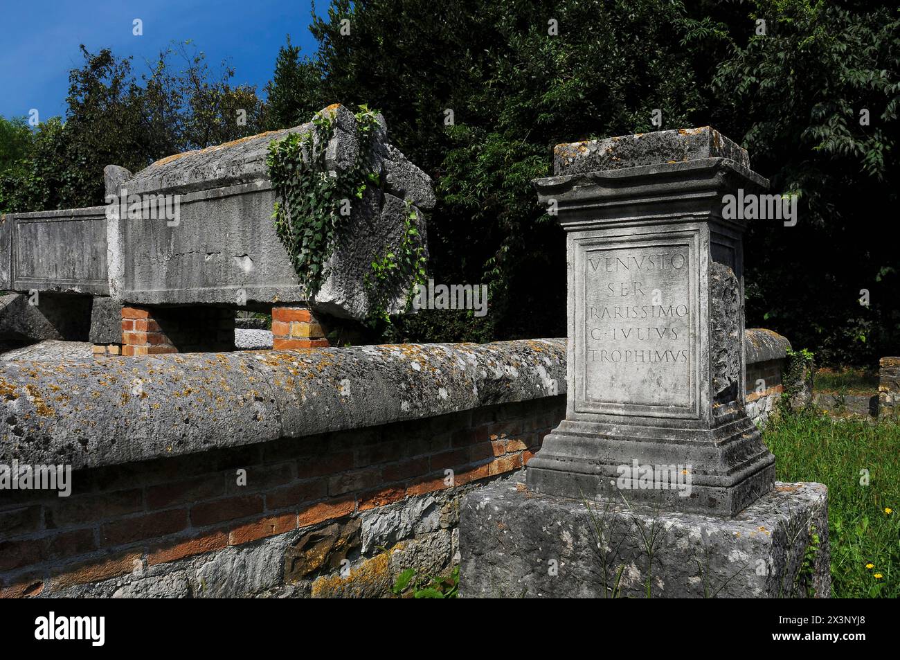 Latin inscription on tomb and sarcophagus resting on modern brick ...