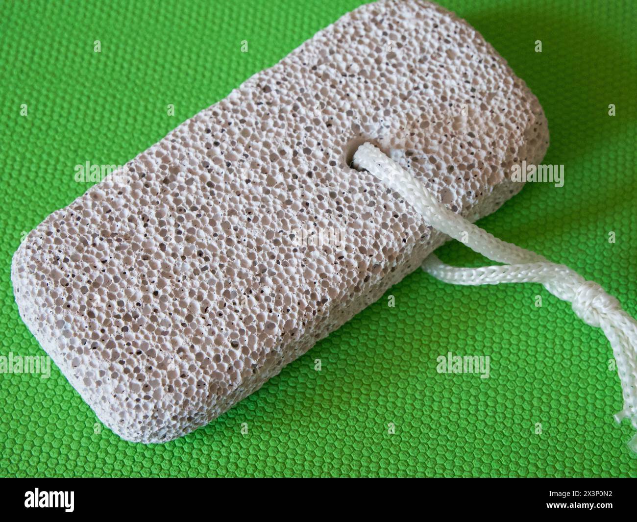 Pumice Stone on Green. A grey pumice stone with a white string on a ...