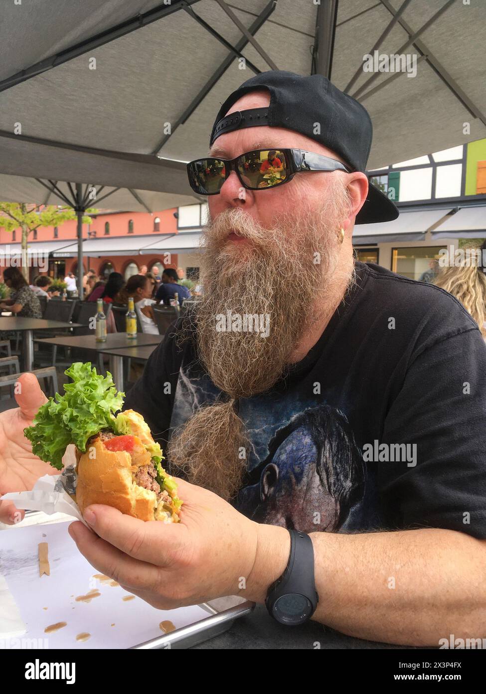 Mann mit langem Bart beißt genüßlich in einen Burger Stock Photo - Alamy