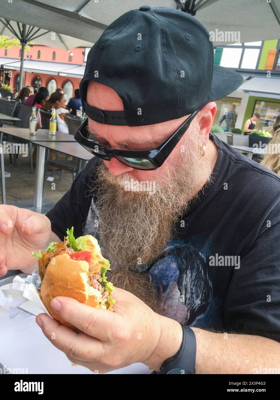 Mann mit langem Bart beißt genüßlich in einen Burger Stock Photo - Alamy