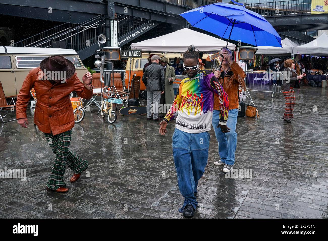 People dance in the rain at a Classic Car Boot sale at Kings Cross in ...