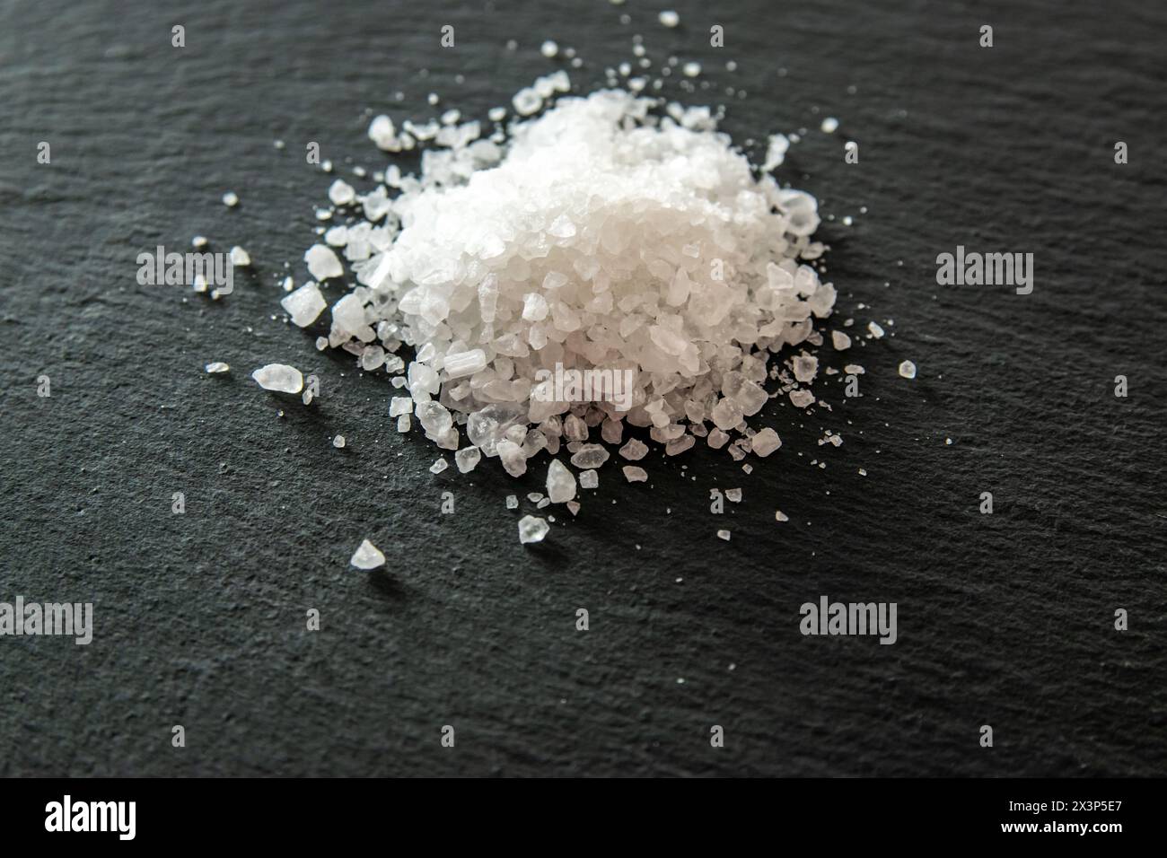 Salt crystals for cooking the food. Pile of sea salt on a black natural ...