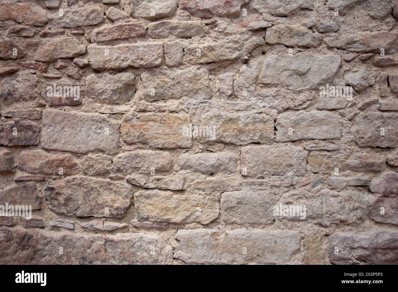 Red structural stone wall of the ancient building consists of old ...