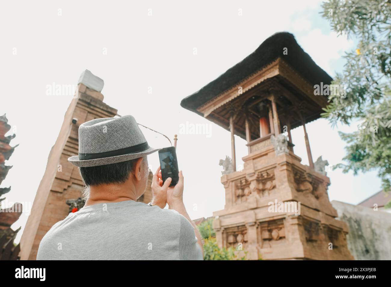 An adult man with grey hat is capturing photo of traditional Balinese ...