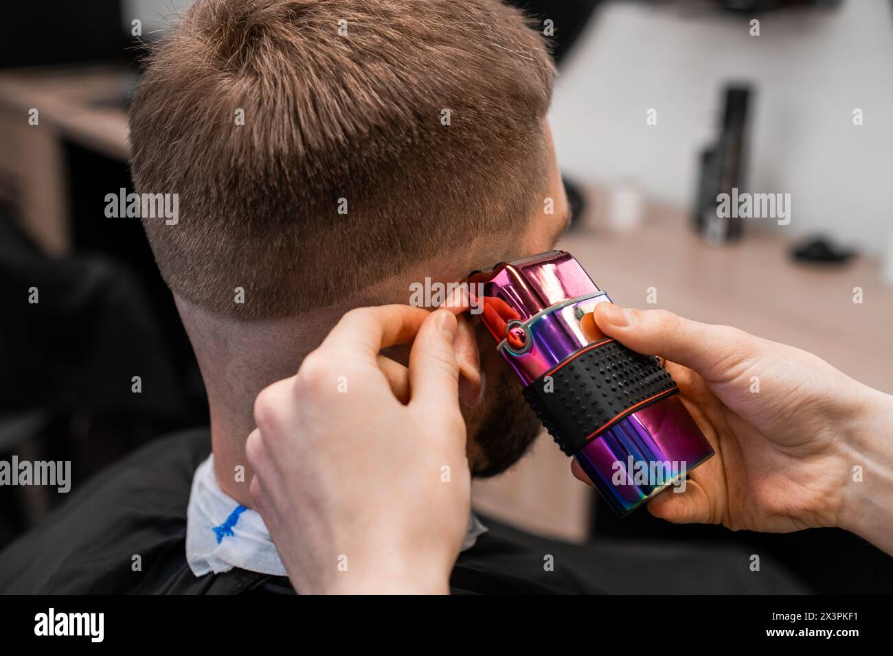 Barber uses shaver machine to cut young man hair in barbershop closeup ...