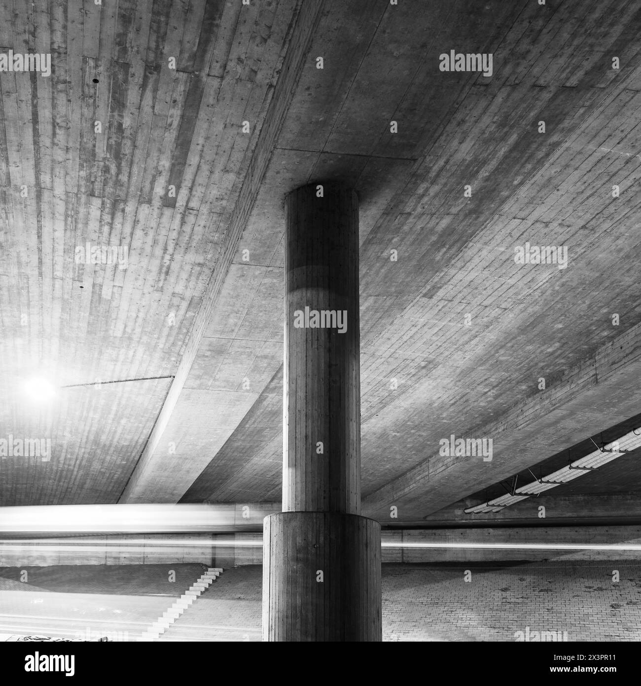 Underpass, with heavy concrete beam, and a single light. Light trails ...