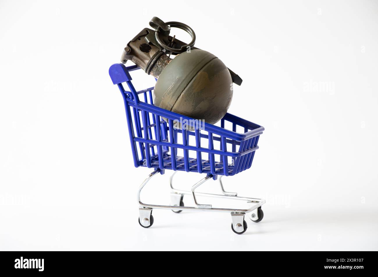 A hand grenade lies in a shopping cart on a white background, gun trade ...