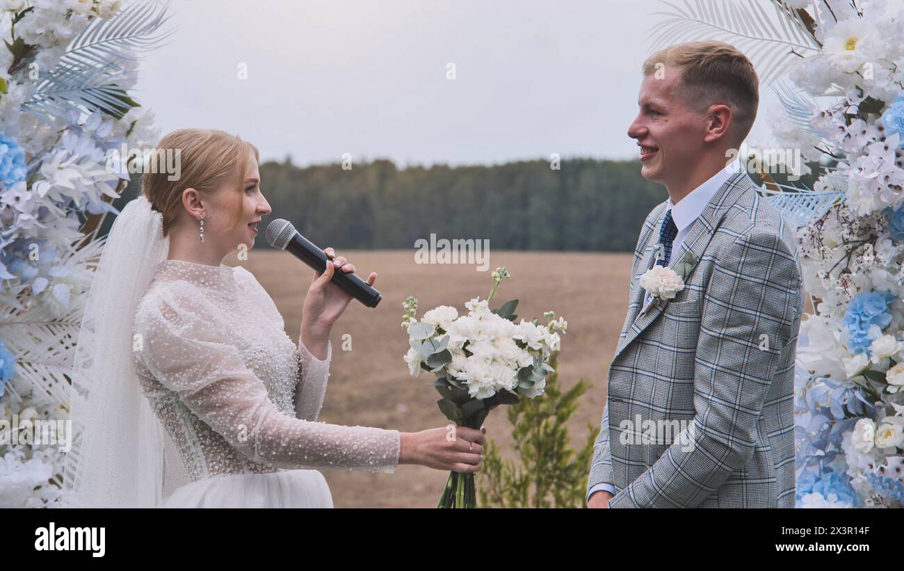 The bride and groom take their vows with a microphone in front of the ...