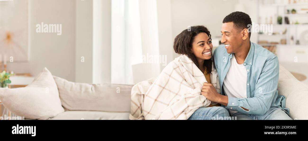 Couple snuggling on couch with blanket at home Stock Photo - Alamy