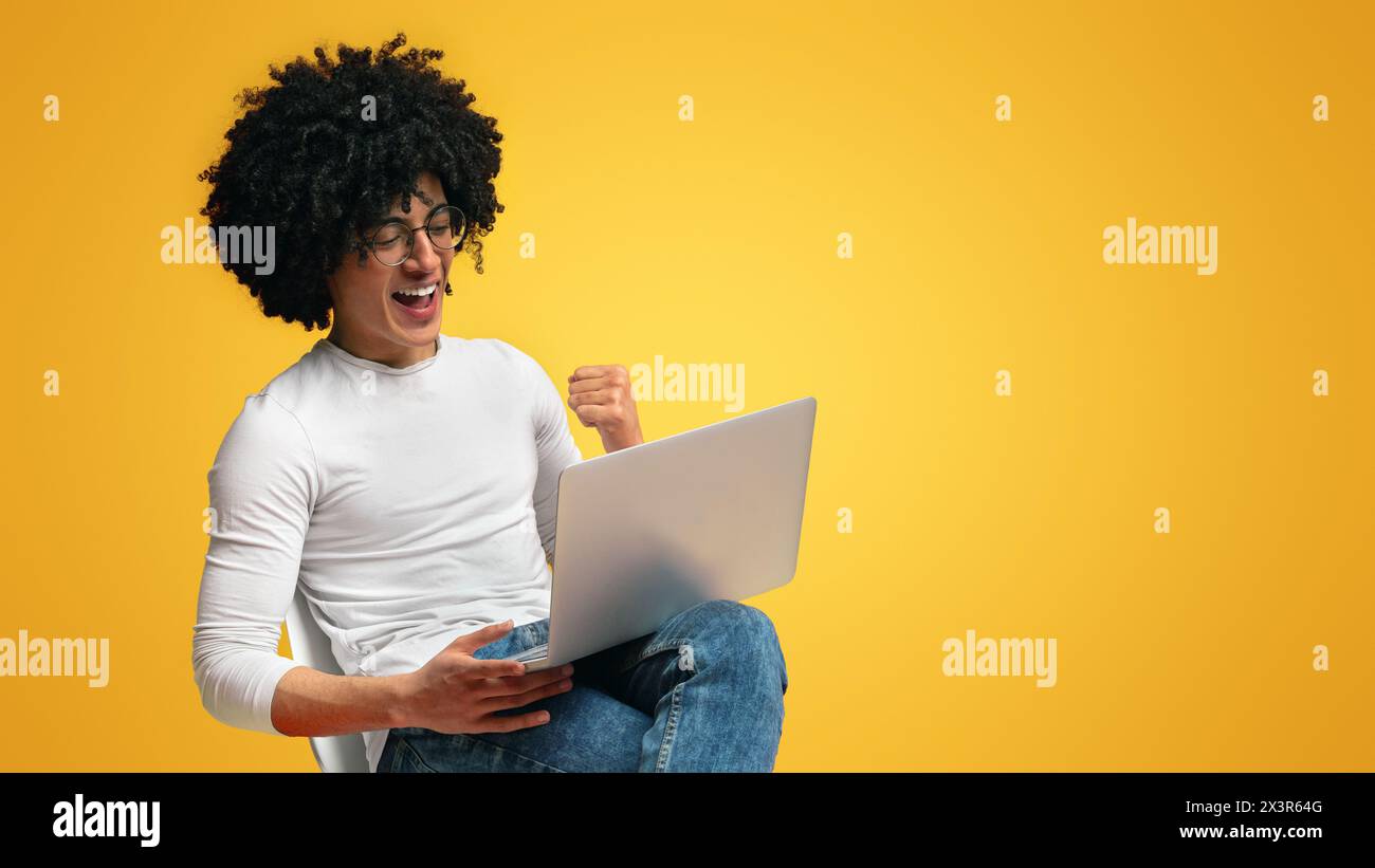 Millennial guy cheering success, looking at laptop Stock Photo - Alamy
