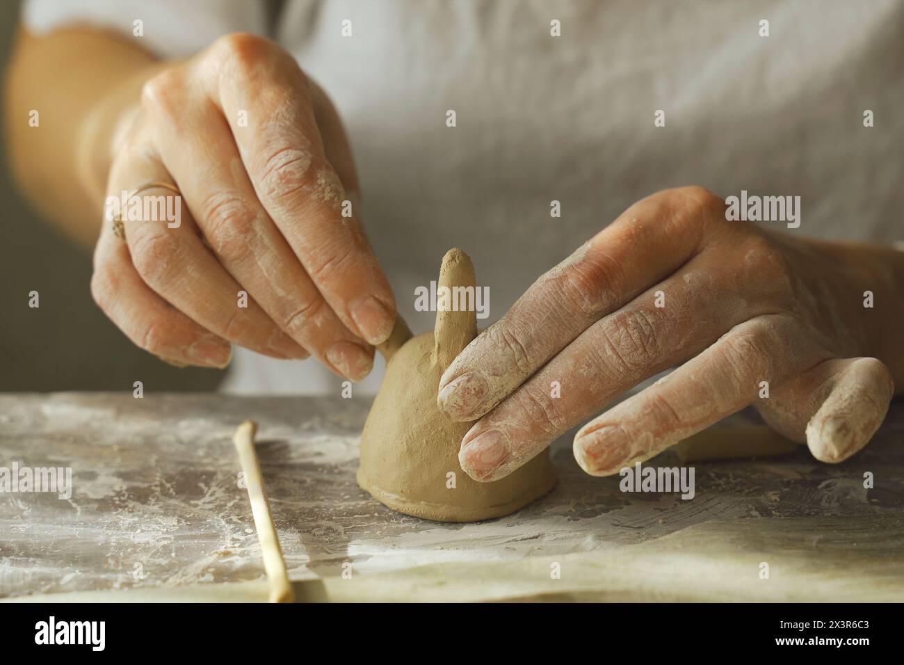 A woman makes a ceramic pot and attaches the legs. Close-up. Creative ...
