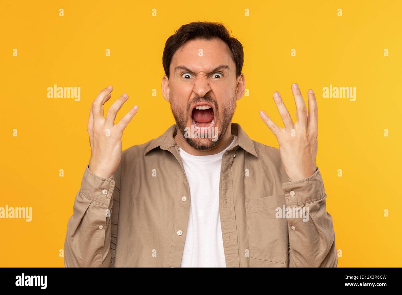 Frustrated Man Expressing Anger With Raised Hands Against Yellow ...