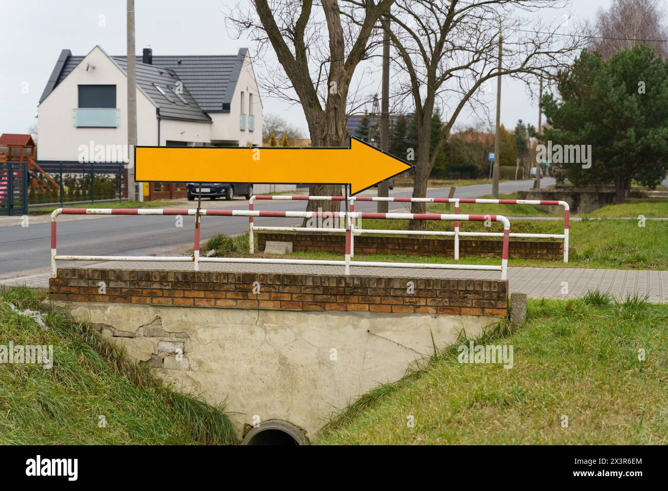 A bright yellow direction arrow sign mounted above a small brick ...