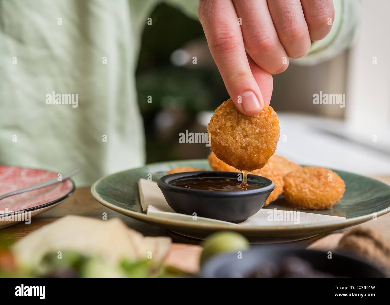 Close up of fried cheese snacks being dipped in sweet chili sauce in a ...