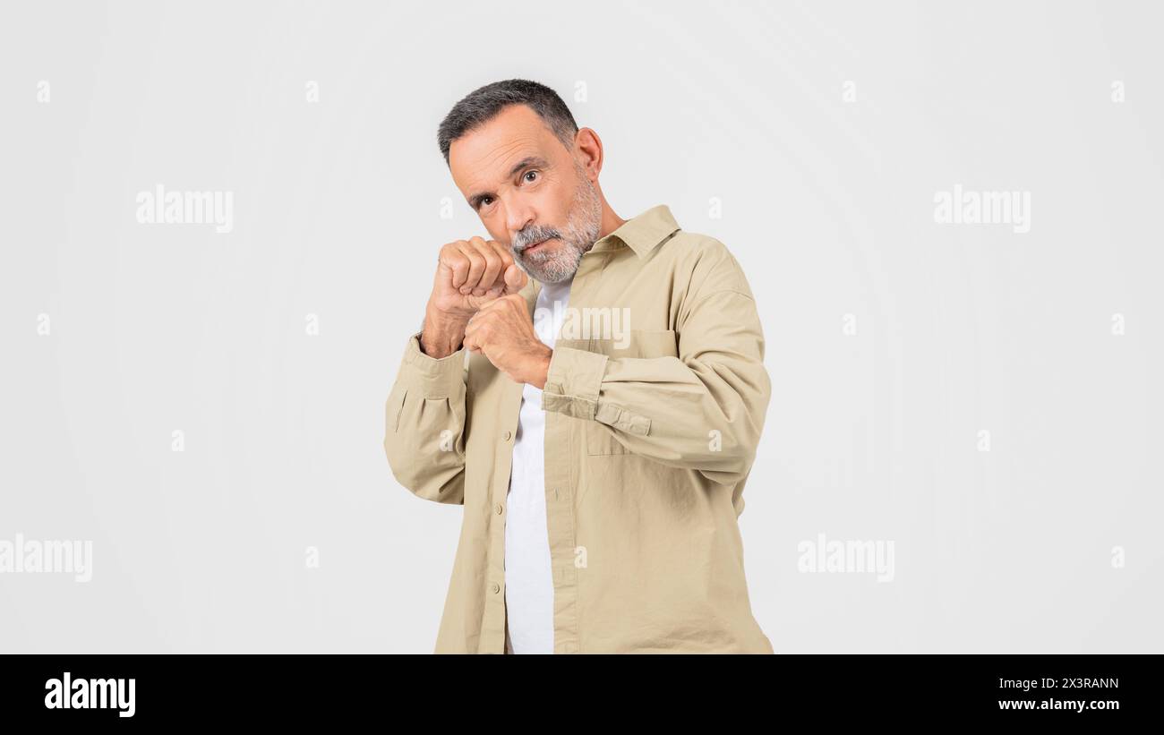 Man in Tan Shirt Holding Hands Together In Fighting Pose Stock Photo ...