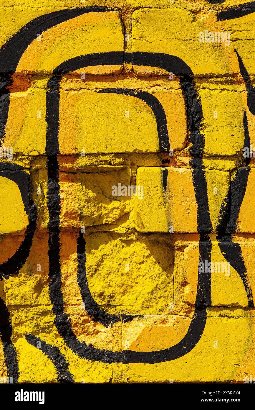 Yellow spray paint, with black ornament, Art on brick wall. Vertical ...
