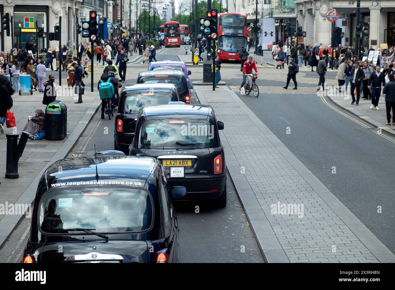 Traffic black taxi cabs queue queuing and pedestrians from rear back behind on Oxford Street in ...