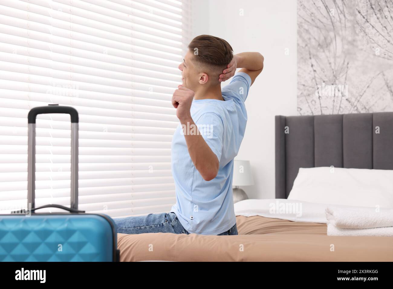 Guest stretching on bed in stylish hotel room Stock Photo - Alamy