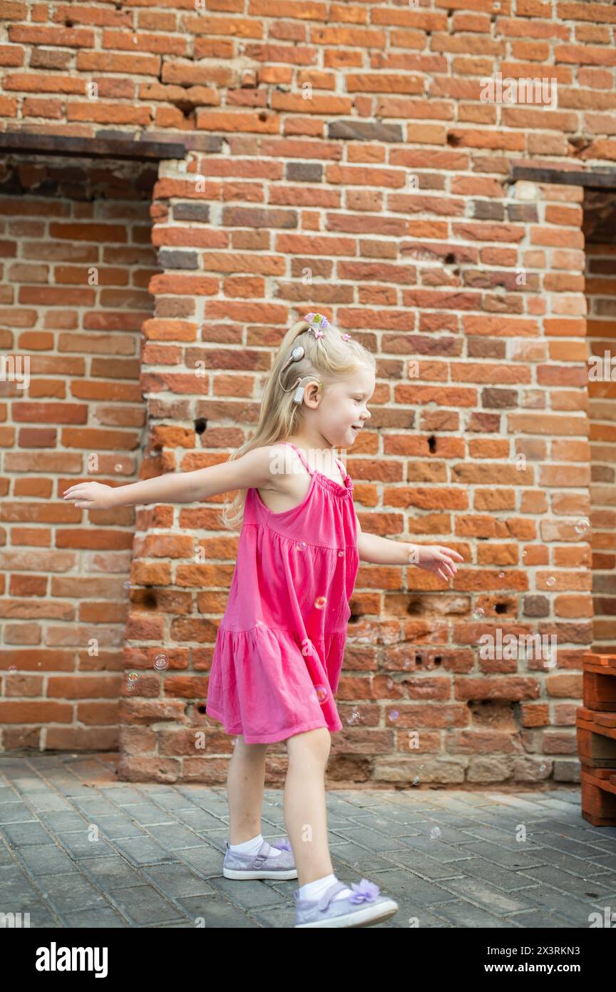Child with hearing problem and cochlear implant plays in street, deaf ...