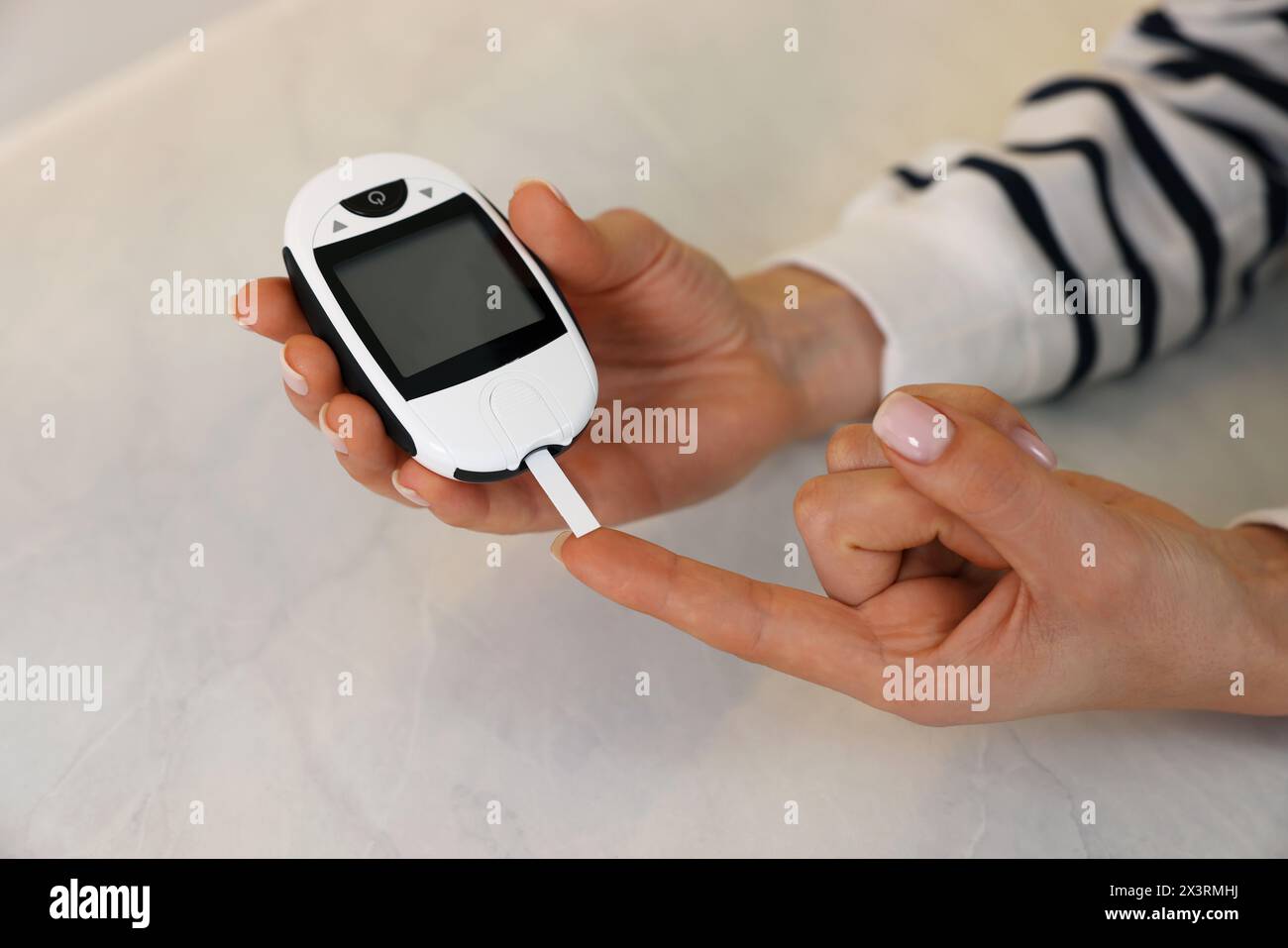 Diabetes. Woman checking blood sugar level with glucometer at light ...