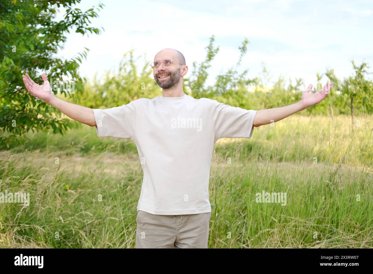 romantic young man stands in vibrant field, arms outstretched as ...