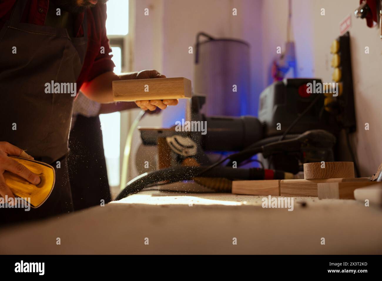 Man in assembly shop using sandpaper for sanding wooden surface before ...