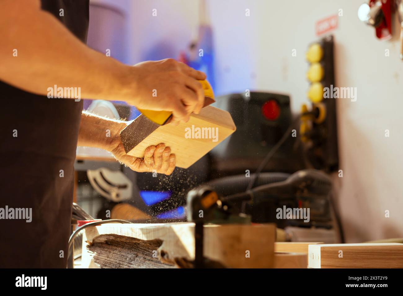 Man in studio using sandpaper for sanding wooden surface before ...