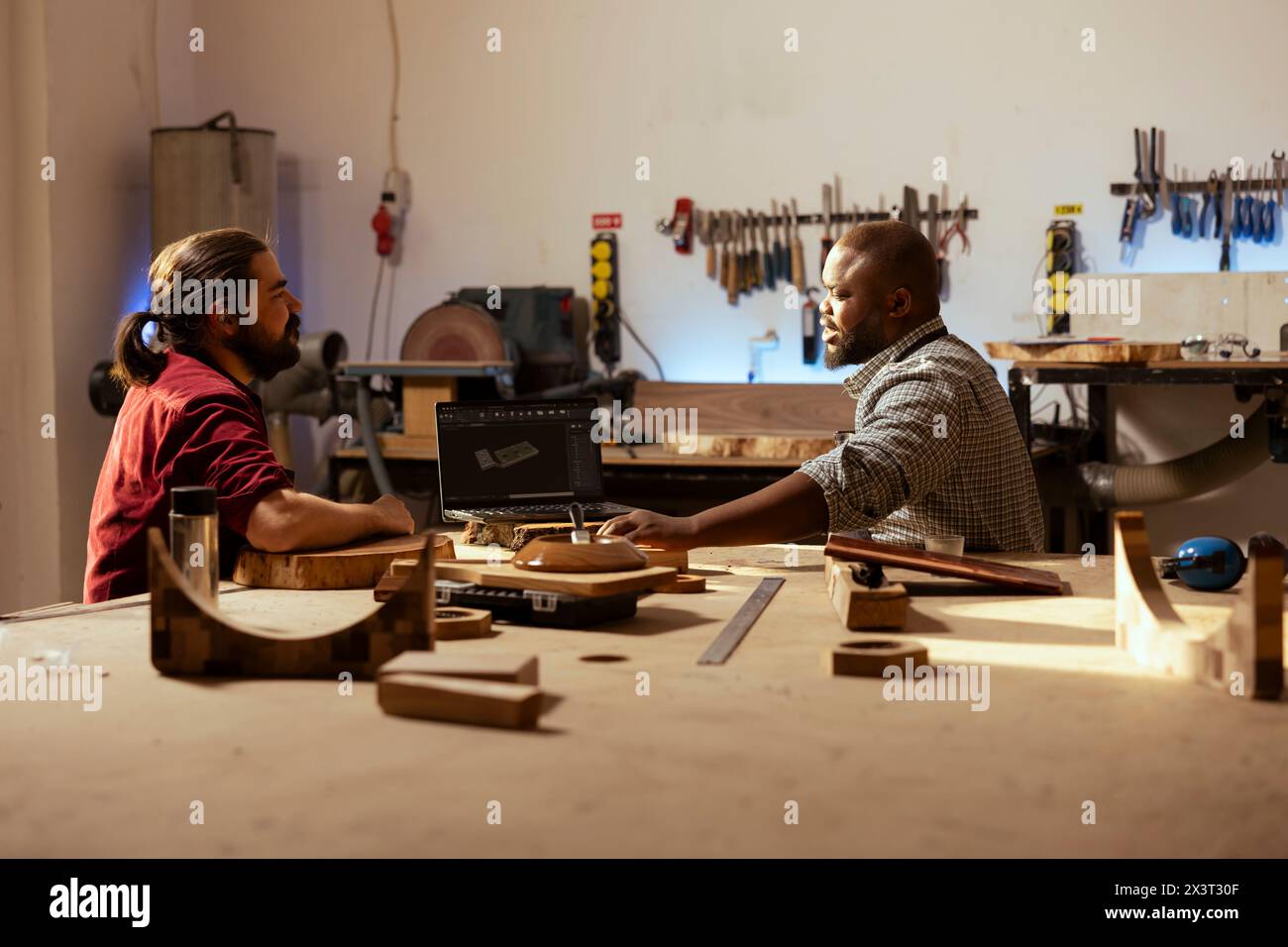 Woodworker and BIPOC coworker using CAD software on laptop to design ...