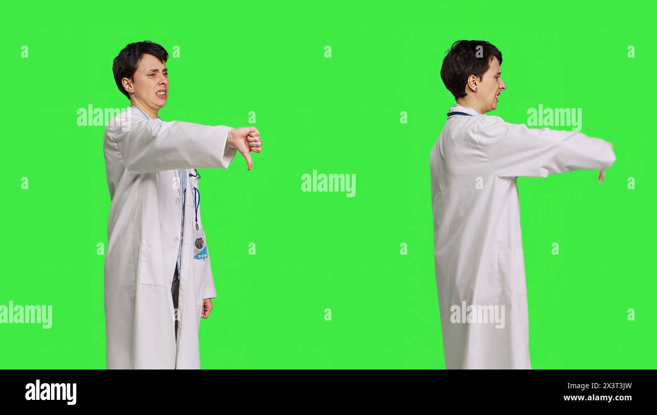 Displeased physician showing thumbs down symbol against greenscreen ...