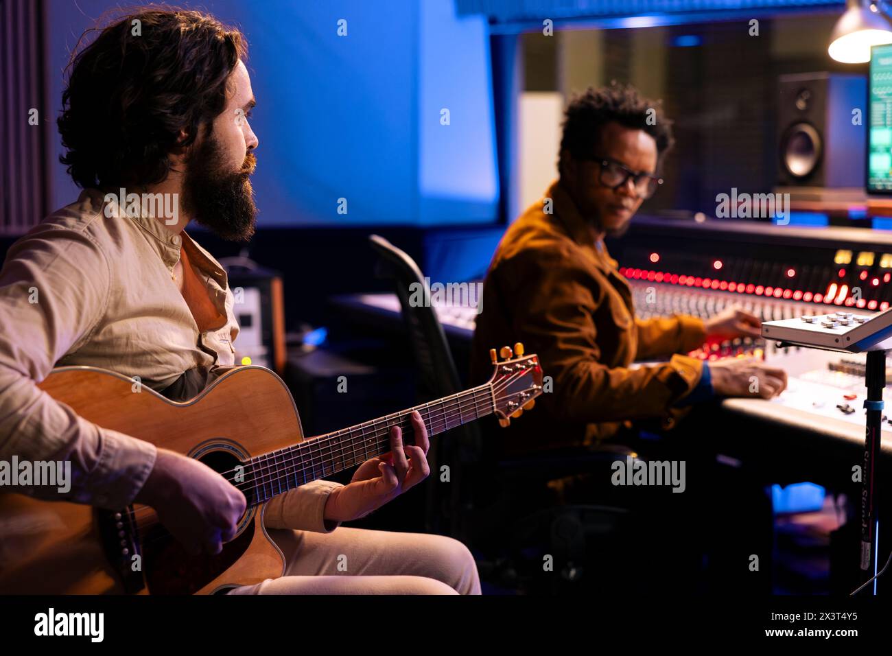 Young singer composer creating a new track on guitar in recording ...